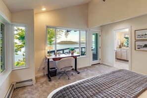 Quarto com cama, escrivaninha e vista para um lago.