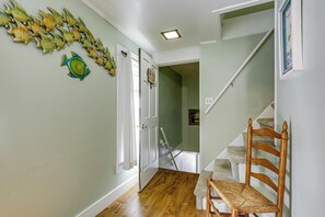 Uma escadaria com uma cadeira de madeira, uma arte de parede com peixes e uma porta que dá para outro quarto.