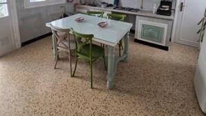 Uma cozinha com mesa de jantar, cadeiras, armários e fogão.