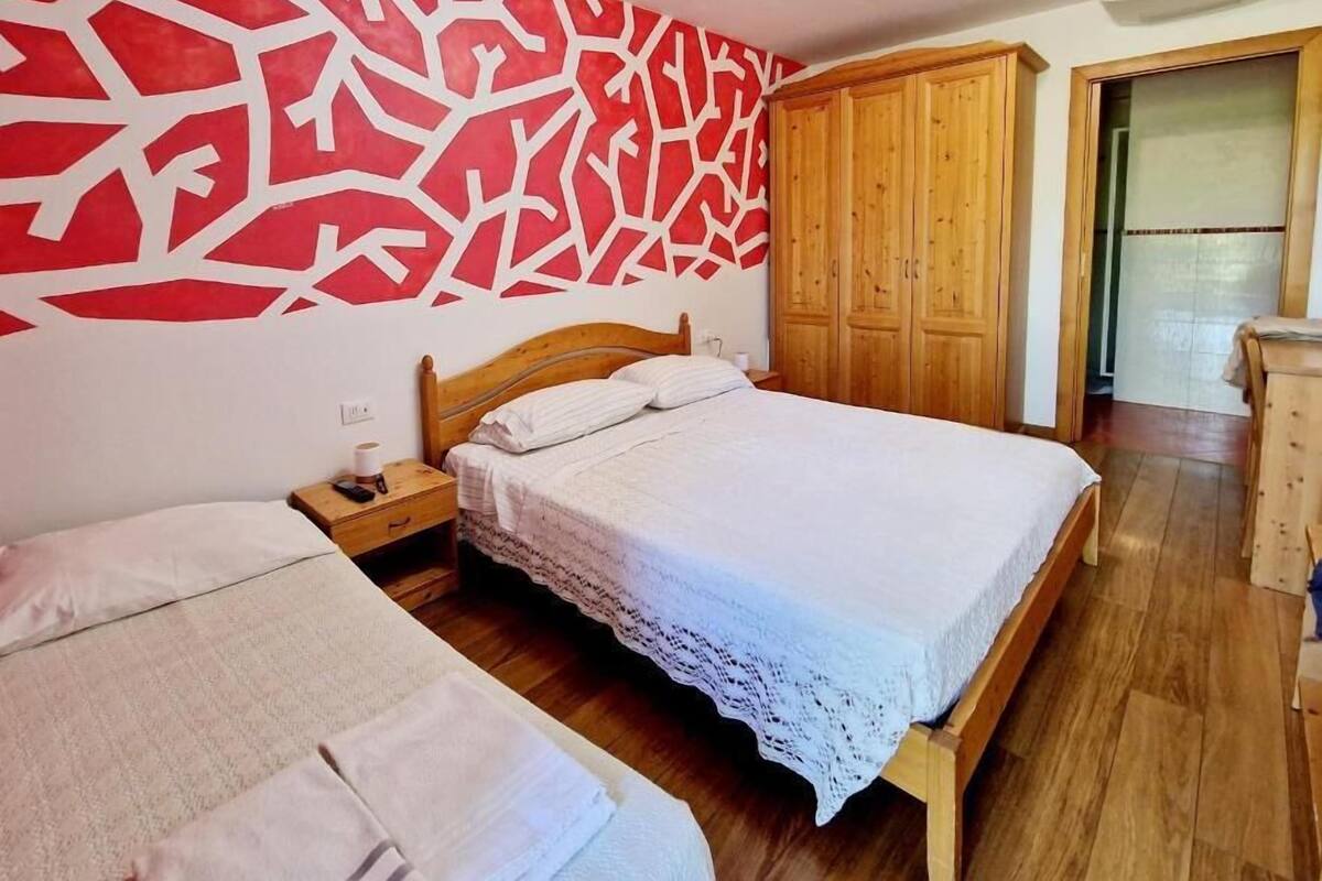 Quarto com cama de madeira, mesa de cabeceira, guarda-roupa e um design de parede abstrato em vermelho.