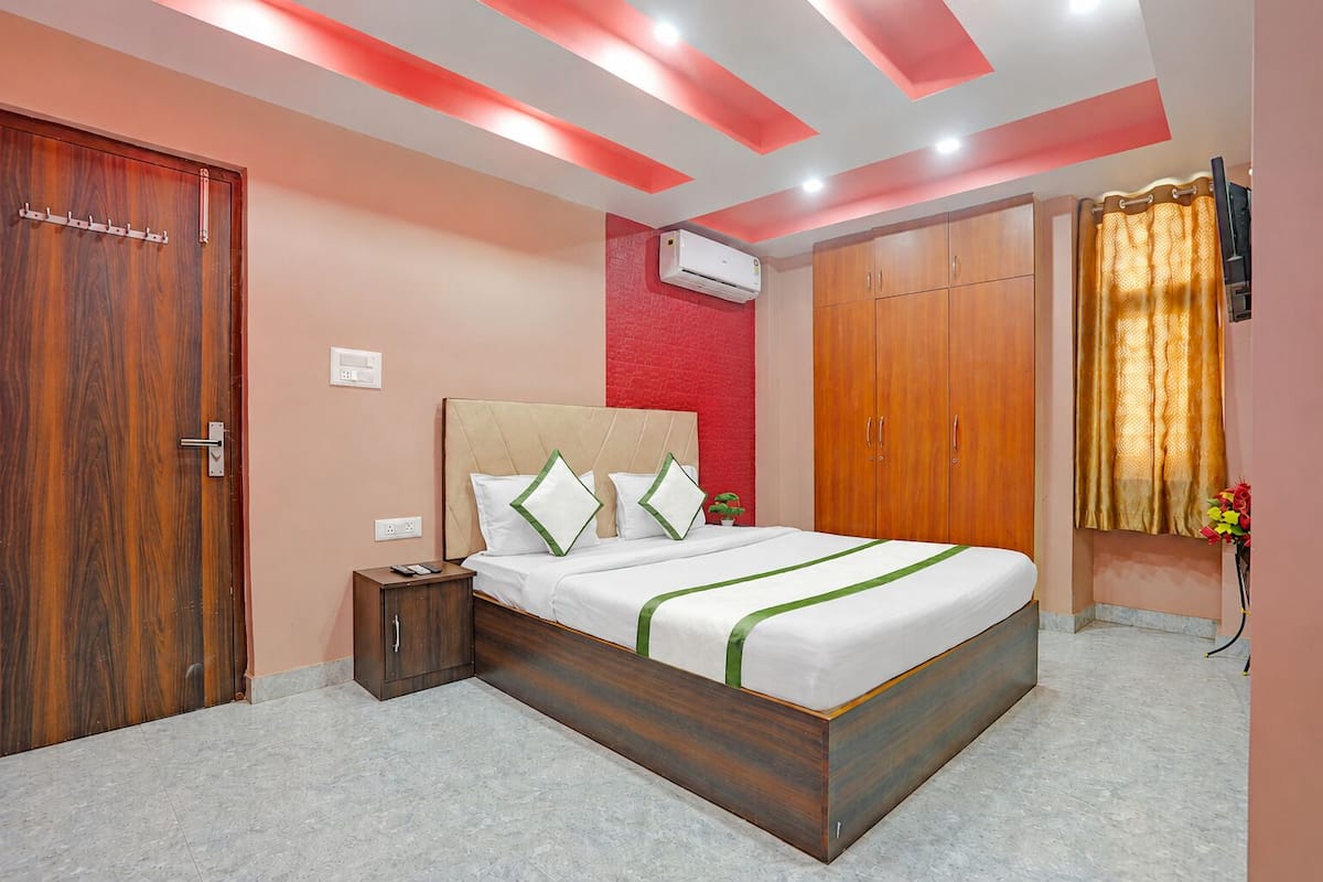 Quarto de hotel com uma cama, guarda-roupa de madeira e uma parede de destaque vermelha.
