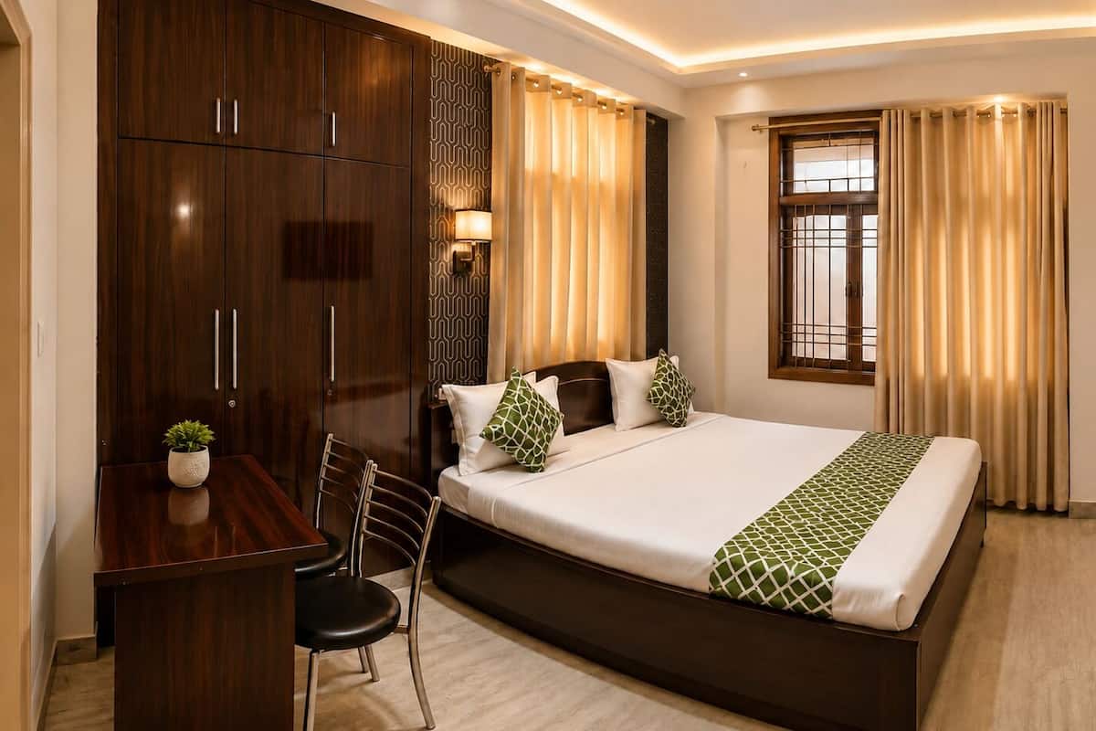 Quarto de hotel com cama, escrivaninha, cadeira, televisão e cortinas.