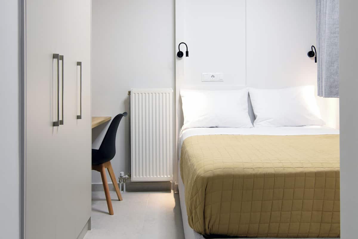 Quarto moderno com cama, mesas de cabeceira, escrivaninha e uma cadeira.