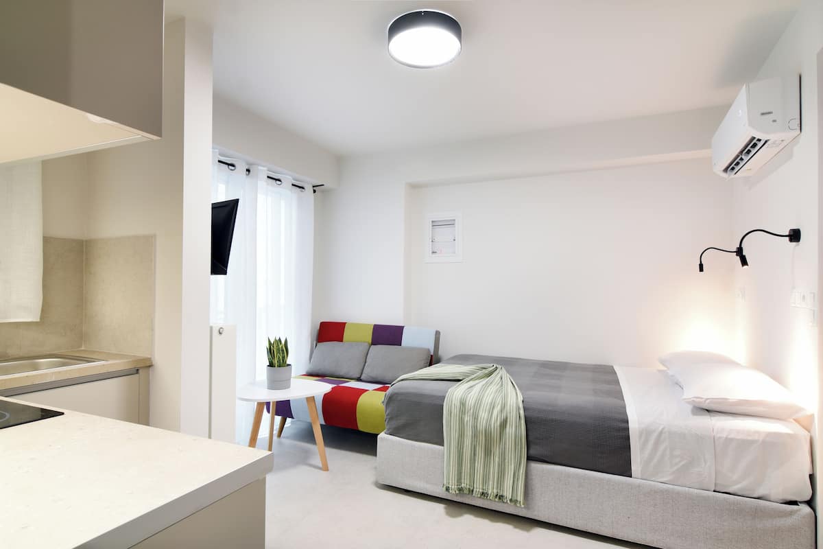Um quarto moderno com cama, mesa de cabeceira e uma pequena escrivaninha com cadeira.