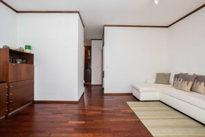 Um quarto com um armário de madeira, um sofá branco com almofadas e um tapete estampado.