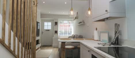 Cozinha moderna com vigas de madeira, luminárias pendentes, ilha central e forno embutido.