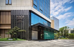 Um edifício moderno com fachada de vidro ampla e sinalização com 'VOCO'.