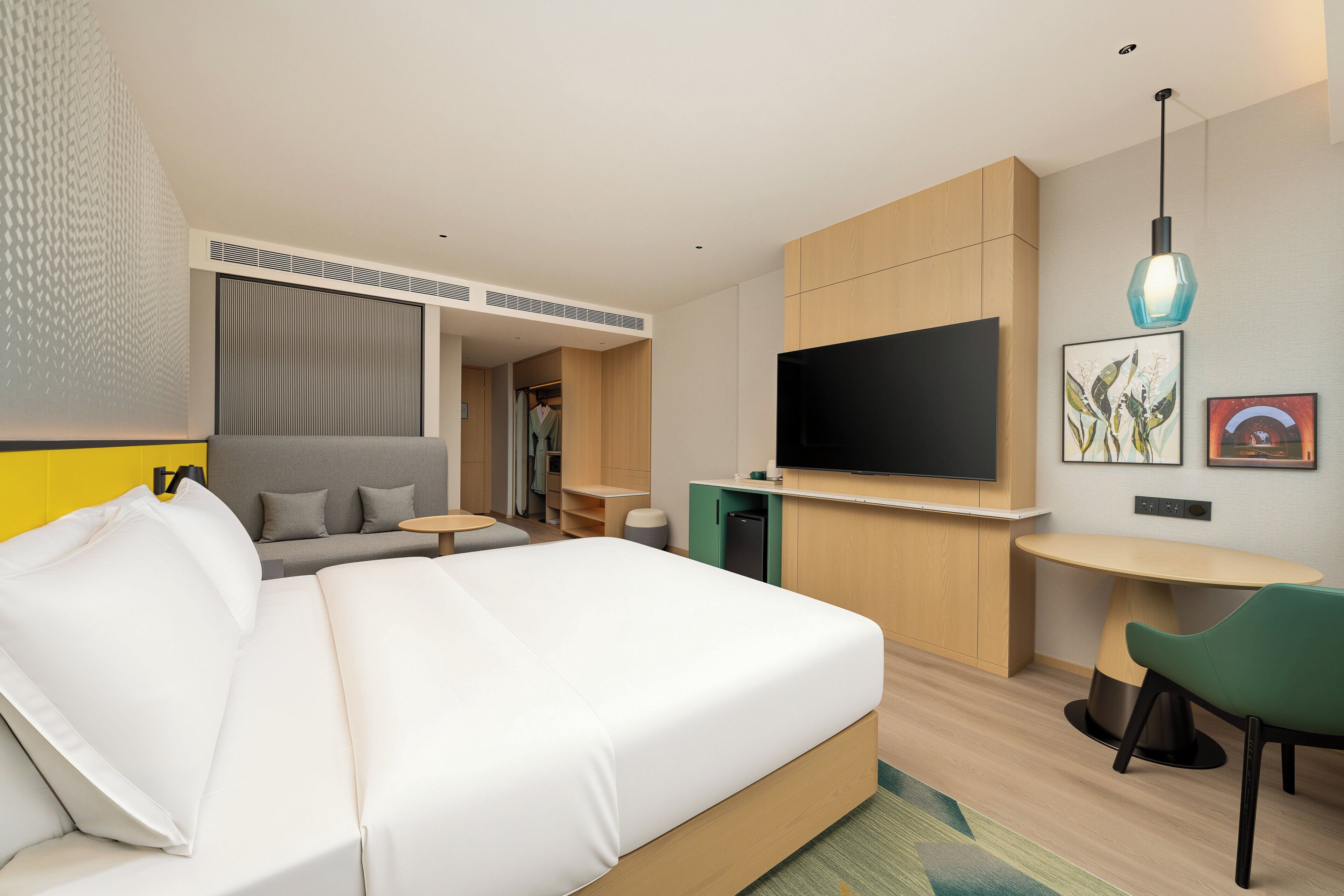 Quarto de hotel moderno com cama, televisão, escrivaninha e cadeira.