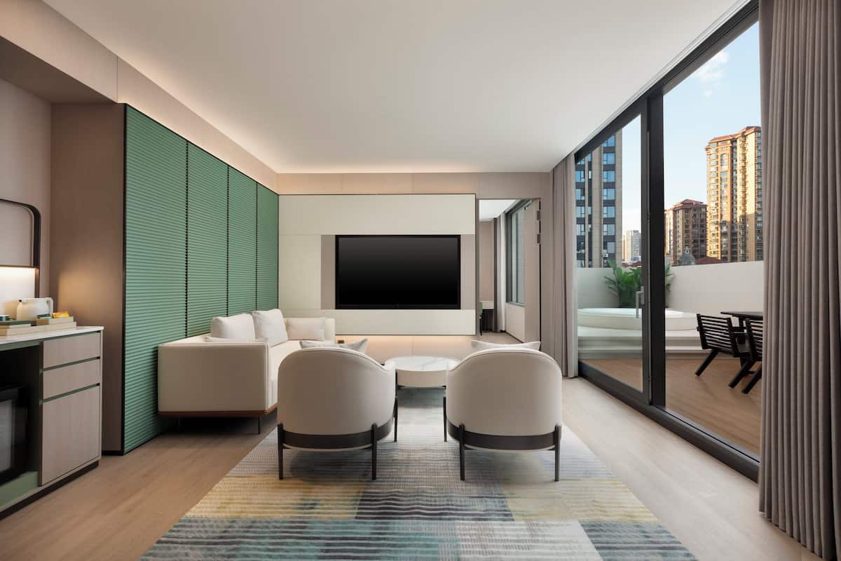 Uma sala de estar moderna com um sofá, duas poltronas, uma mesa de centro e uma televisão.