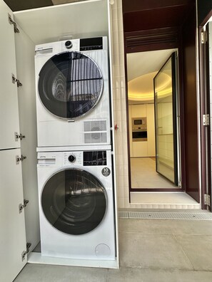 Uma máquina de lavar e secar empilhadas, com uma porta para uma lavanderia.