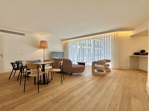 Uma sala de estar moderna com uma mesa de jantar, cadeiras, um sofá e um abajur.