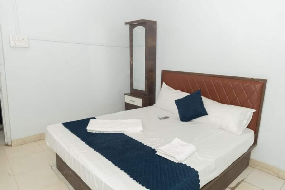 Cama bem arrumada com cabeceira marrom, espelho e manta azul.