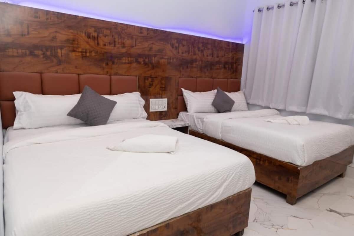 Quarto de hotel com duas camas, cabeceira de madeira, roupa de cama branca e painel de parede de madeira.