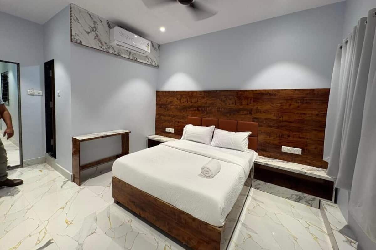 Quarto moderno com cabeceira de madeira, uma cama grande, mesas de cabeceira e um ventilador de teto.