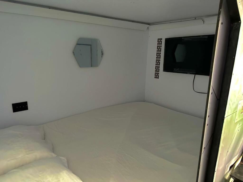 Quarto com cama, televisão na parede e ar condicionado.