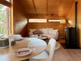Interior acolhedor de cabana com área de jantar, sofá e lareira.