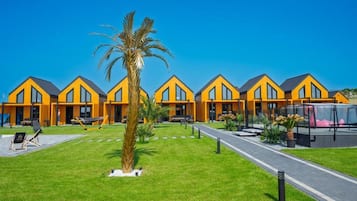 Uma fileira de edifícios amarelos com grandes janelas, uma palmeira central e céu claro.