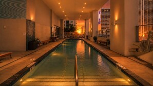 Área da piscina com vista para o pôr do sol, bancos e escada que leva a um andar superior.
