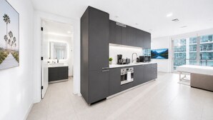 Cozinha moderna com armários escuros, forno embutido e uma janela grande.