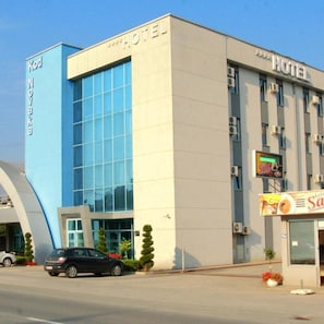 Edifício de hotel com design moderno, com grandes janelas e um letreiro 'HOTEL' chamativo na fachada.