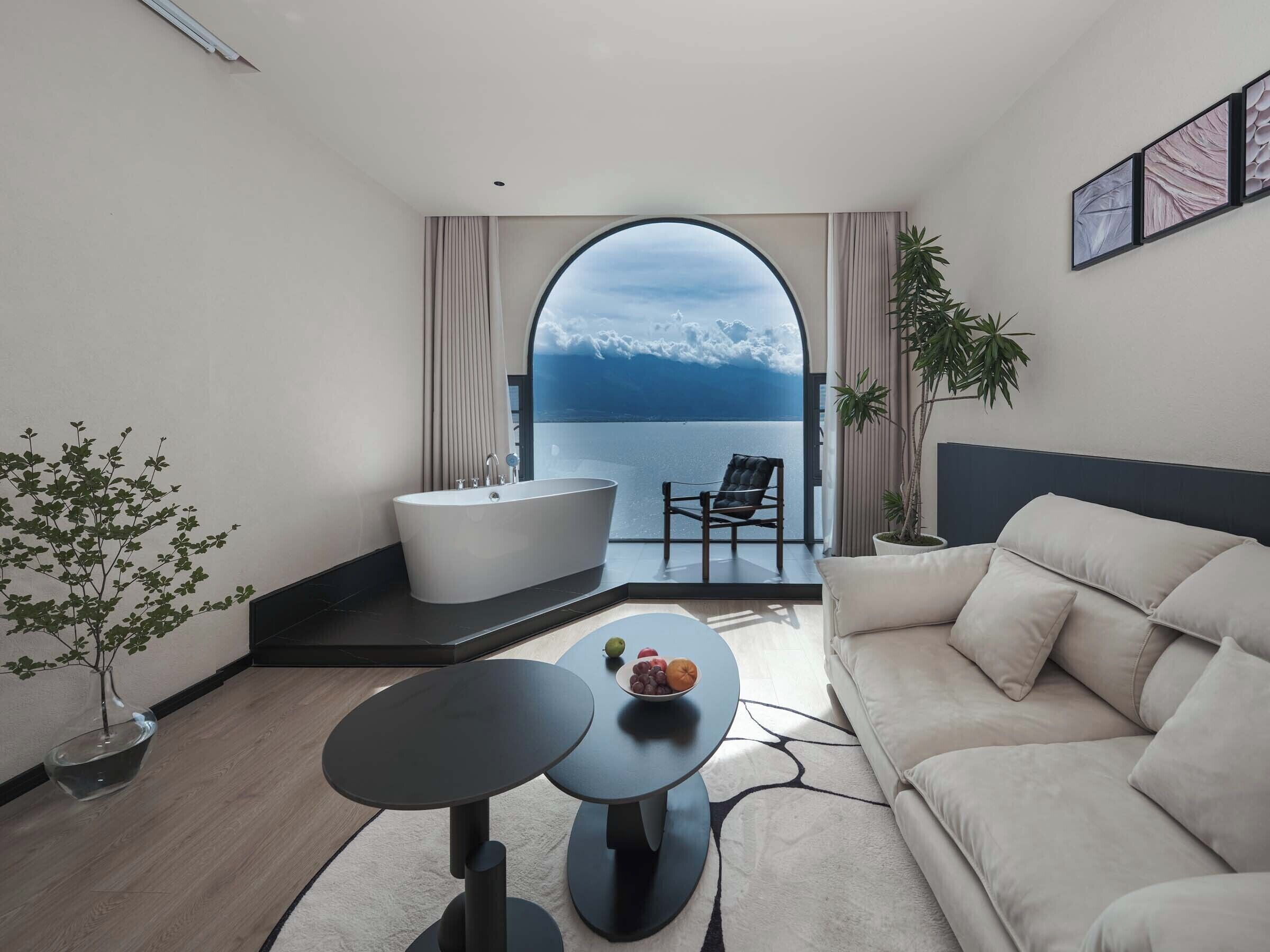 Uma sala de estar moderna com sofá, mesa de centro redonda, banheira e vista para o mar por uma janela em arco.