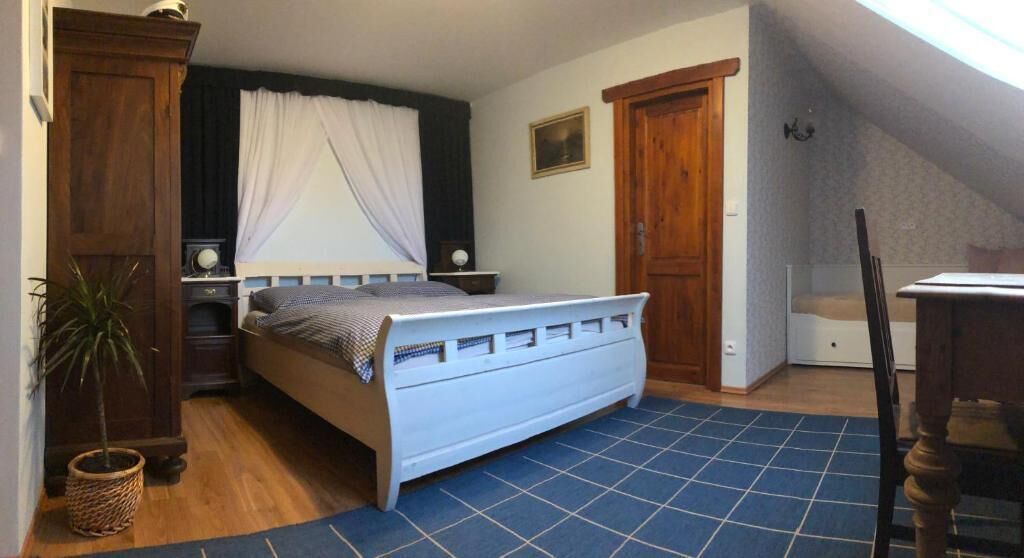 Quarto com cama, guarda-roupa de madeira, mesa de cabeceira, luminária e um vaso de planta.