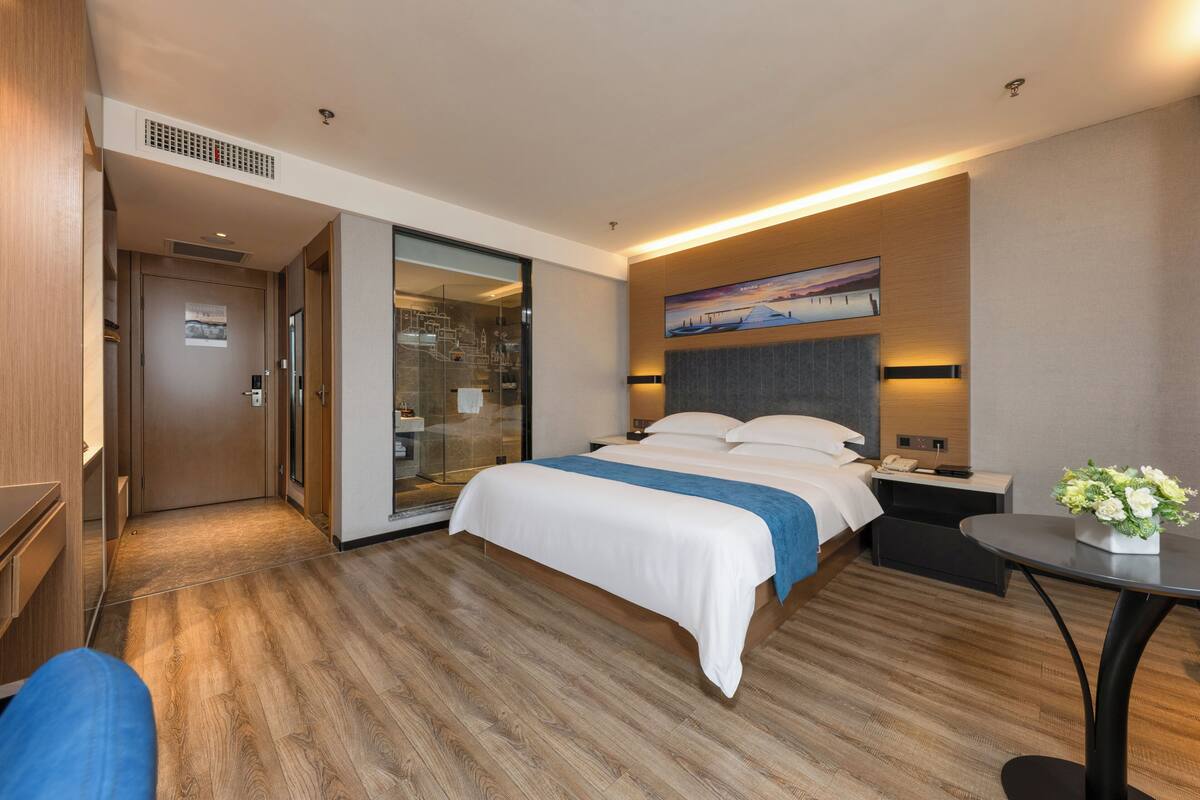 Quarto de hotel com cama, mesa de cabeceira e vista para a cidade.