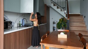 Uma cozinha moderna com uma mesa de jantar de madeira, uma escada e uma ilha de cozinha.