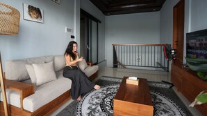 Uma sala de estar com um sofá, uma mesa de centro de madeira, um tapete estampado e uma televisão.