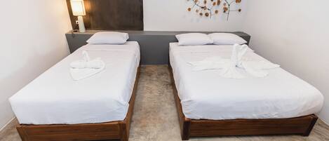 Quarto de hotel com duas camas, ar condicionado fixado na parede, um objeto decorativo na parede e um abajur.