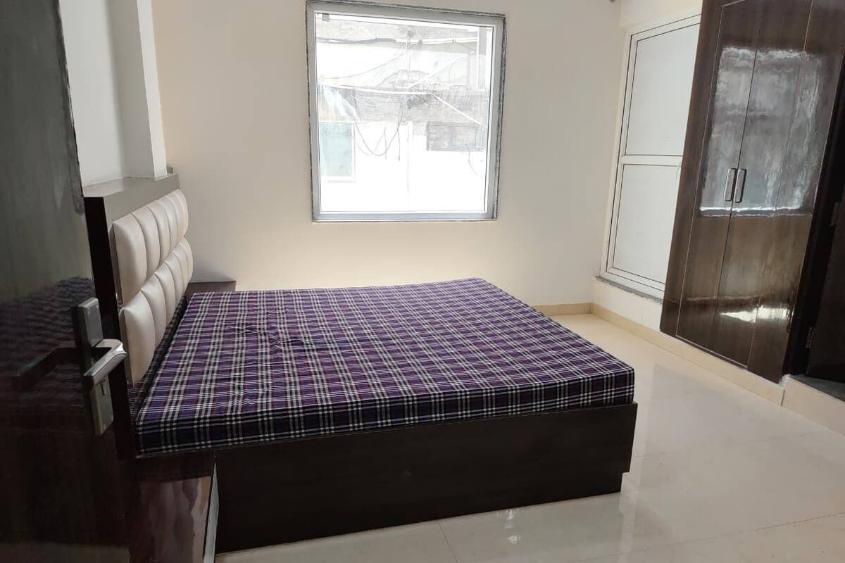 Um quarto com cama, janela, guarda-roupa e uma cadeira.