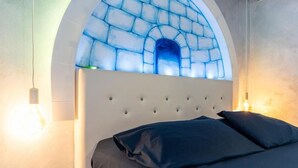 Quarto com uma janela em arco singular, cabeceira estofada e abajures.