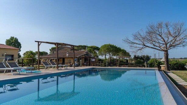 Piscina límpida com espreguiçadeiras e um espaço de estar coberto.