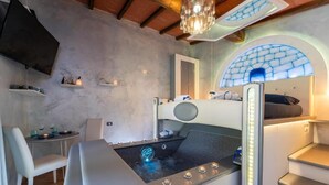 Quarto moderno com hidromassagem integrada, área de jantar e espaço de estar aconchegante com lareira.