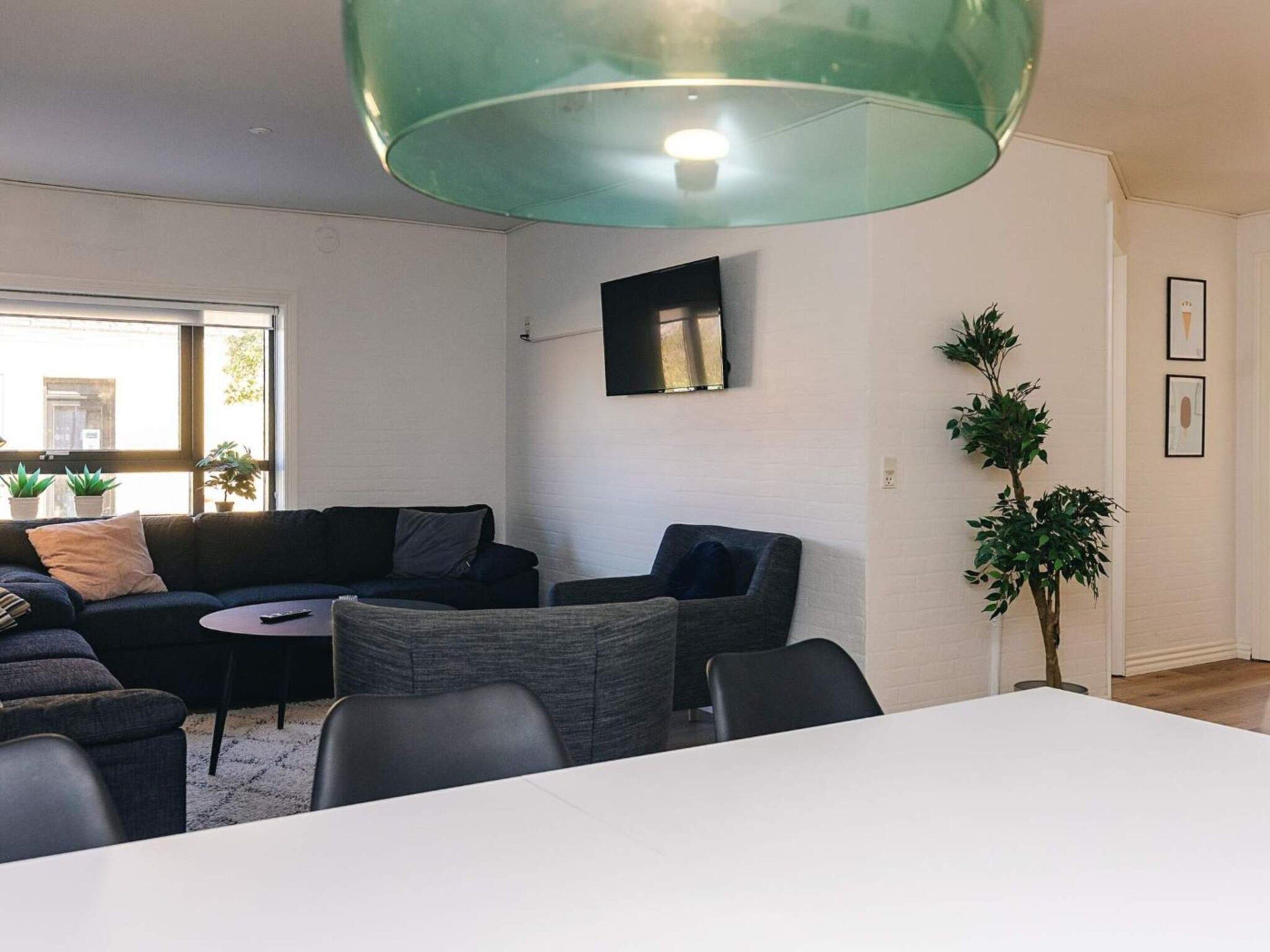 Uma sala de estar moderna com sofá, cadeiras, uma mesa de jantar e uma janela grande.