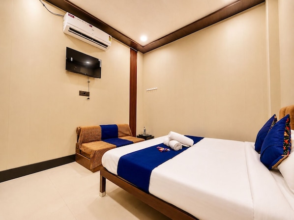 Quarto de hotel com cama, sofá, televisão de tela plana e ar condicionado.