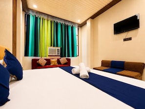 Quarto de hotel com cama, televisão e janela com cortinas.