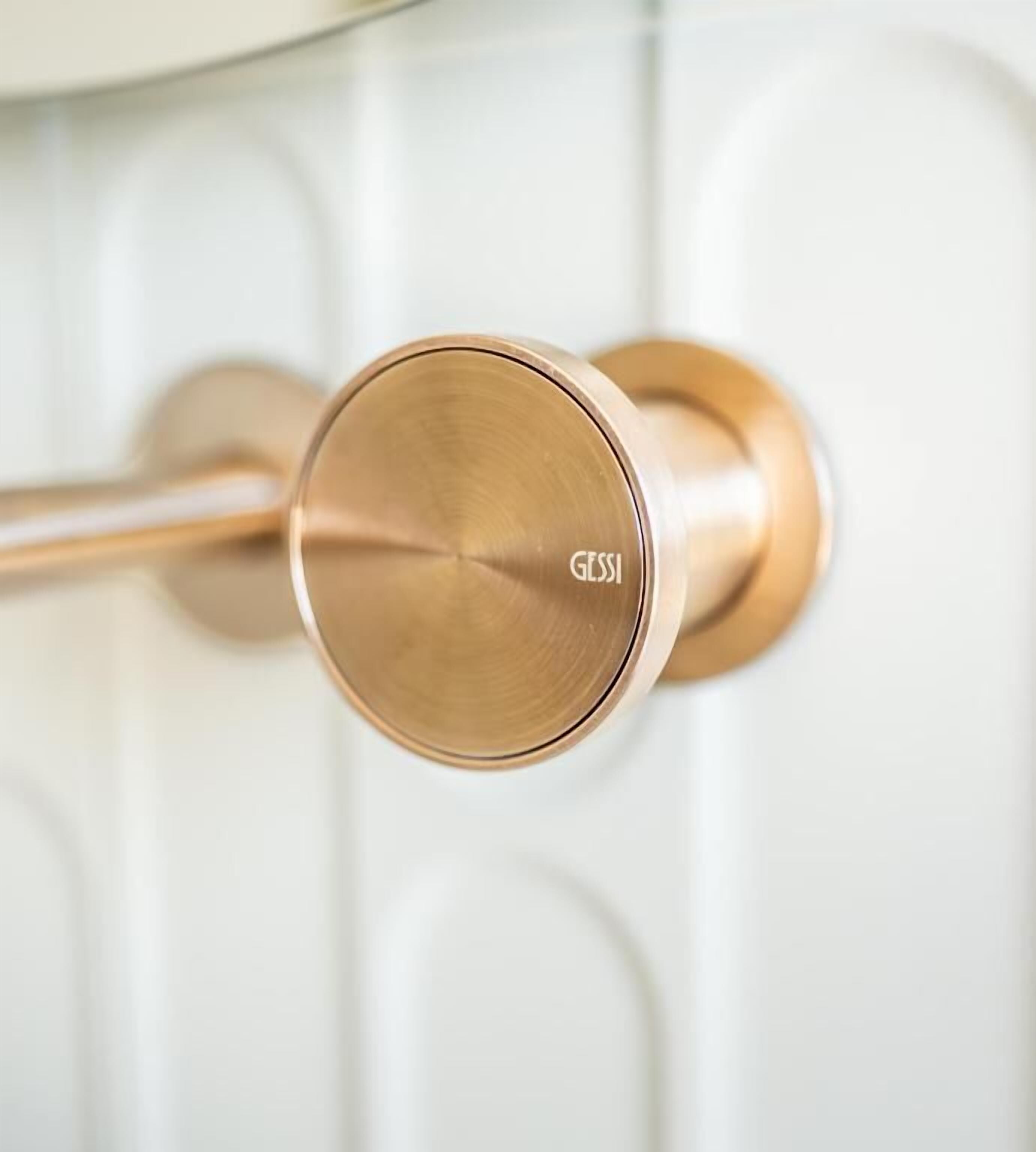 Uma maçaneta de latão com o nome da marca 'GESSI' numa porta branca.
