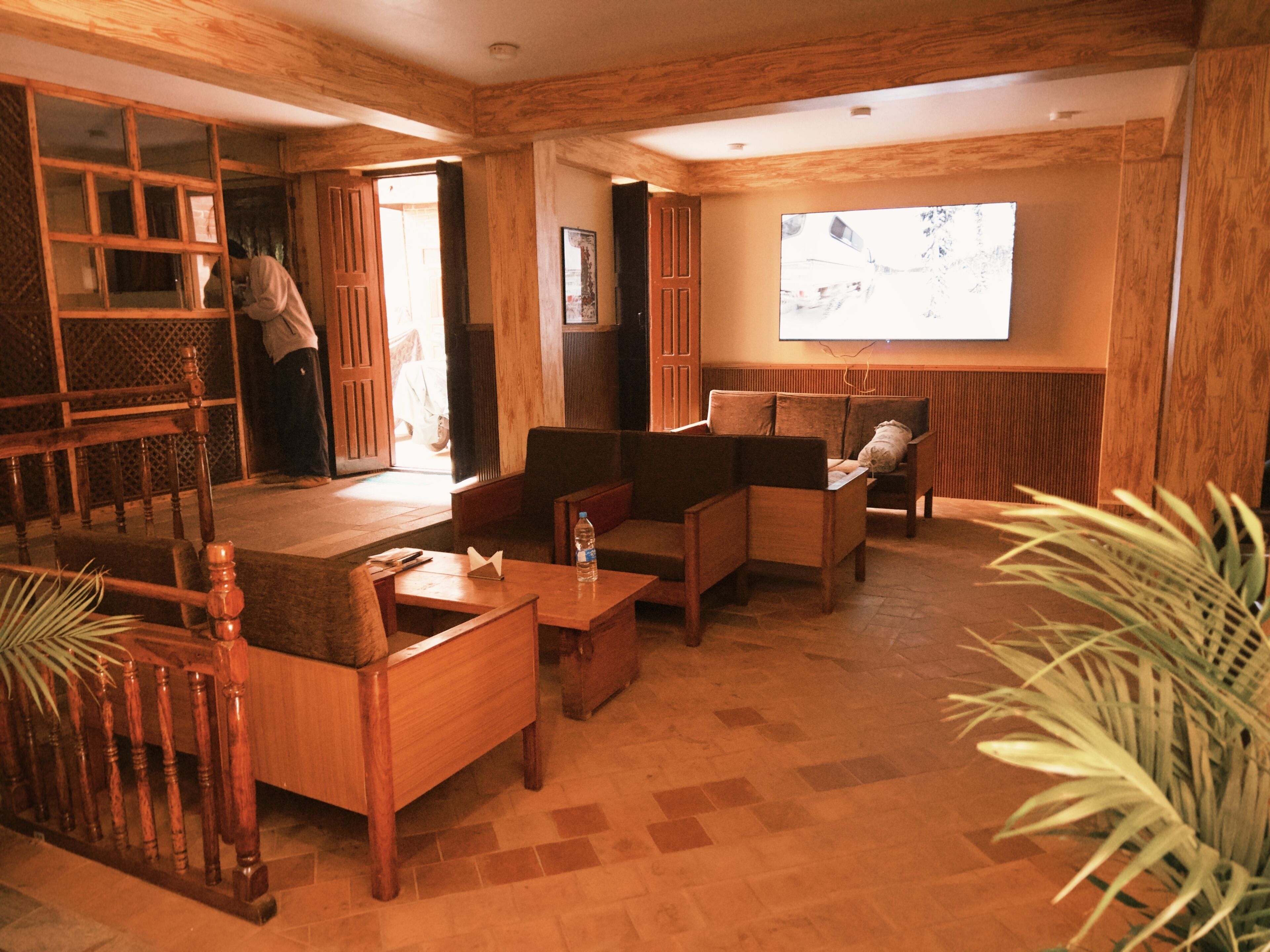 Uma ampla sala de estar com mobiliário de madeira, uma televisão e uma janela grande.