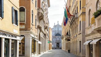 Rua com edifícios históricos, uma igreja ao longe e bandeiras.