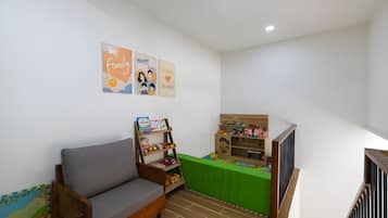 Espaço infantil com sofá, prateleiras e cozinha de brincar.