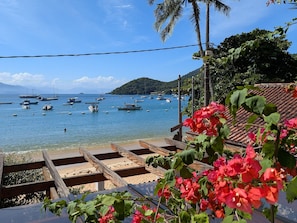 Vista costeira com barcos, um deck de madeira e paisagem tropical.