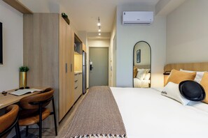 Quarto de hotel com cama, escrivaninha e guarda-roupa.