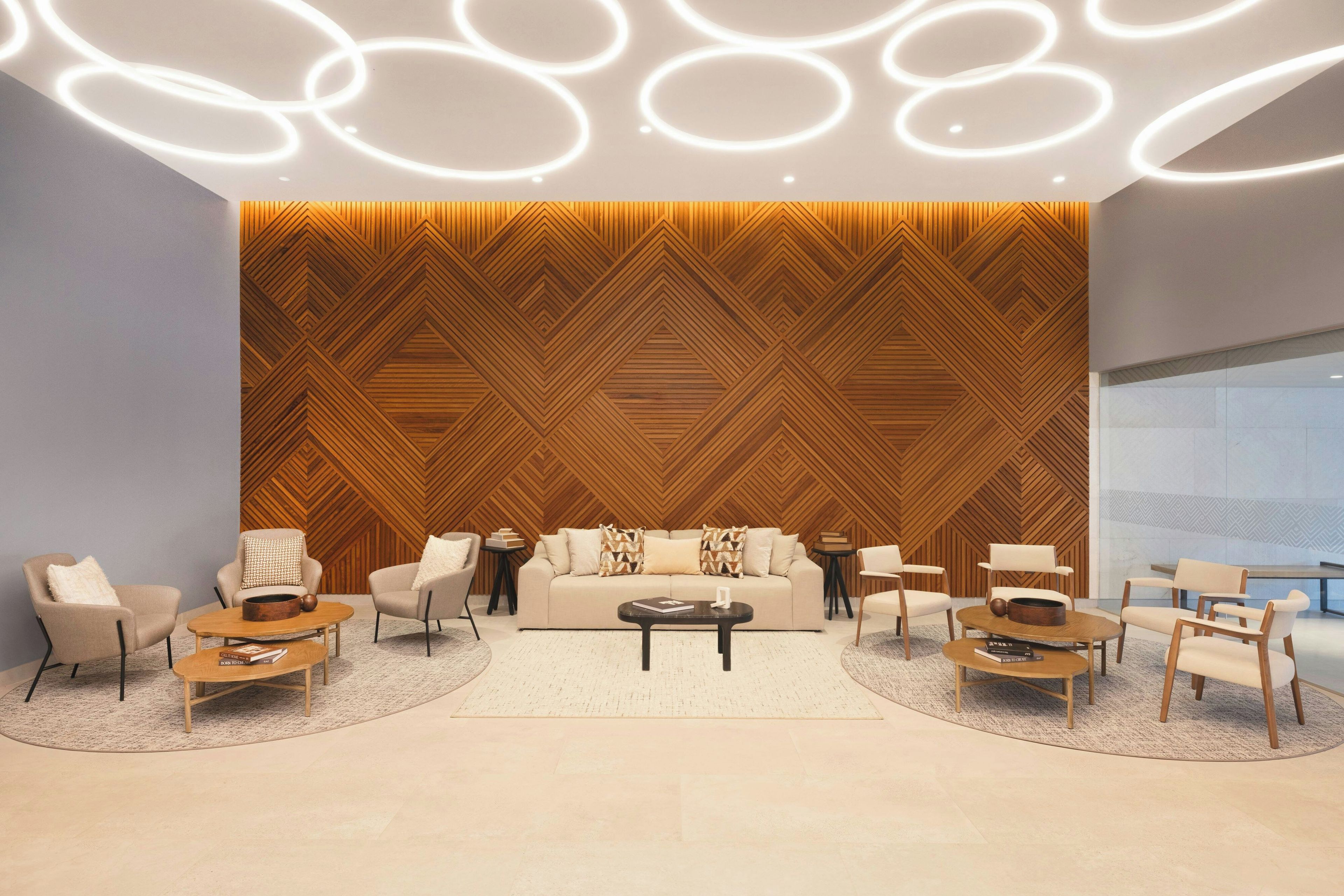 Uma sala de estar moderna com parede estampada em padrão geométrico, um conjunto de sofás e uma mesa de centro.