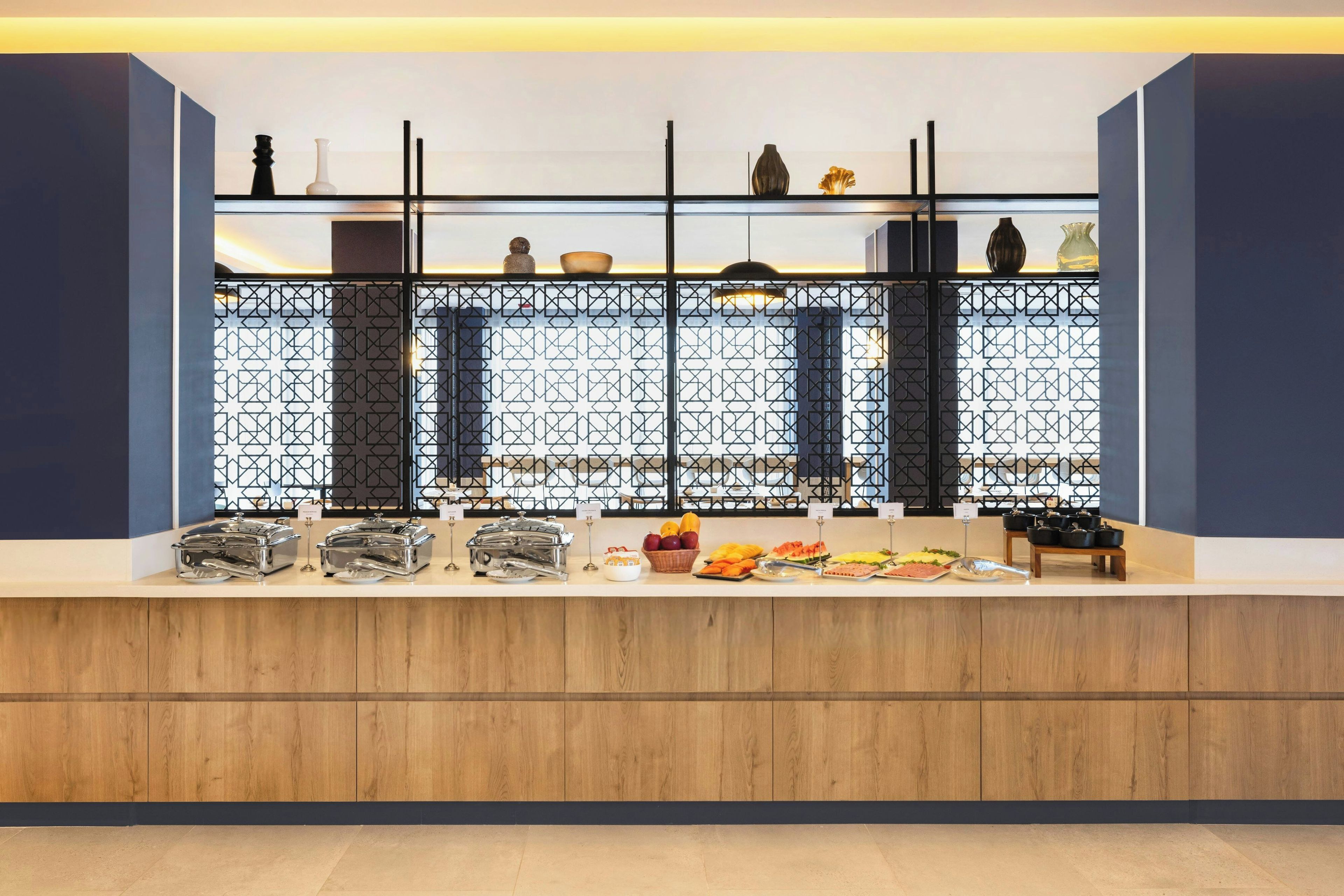 Disposição de buffet com diversos alimentos e objetos decorativos em prateleiras.