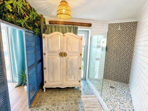 Casa de banho com soalho em azulejos estampados, armário branco com puxadores de latão e área de duche com azulejos decorativos.