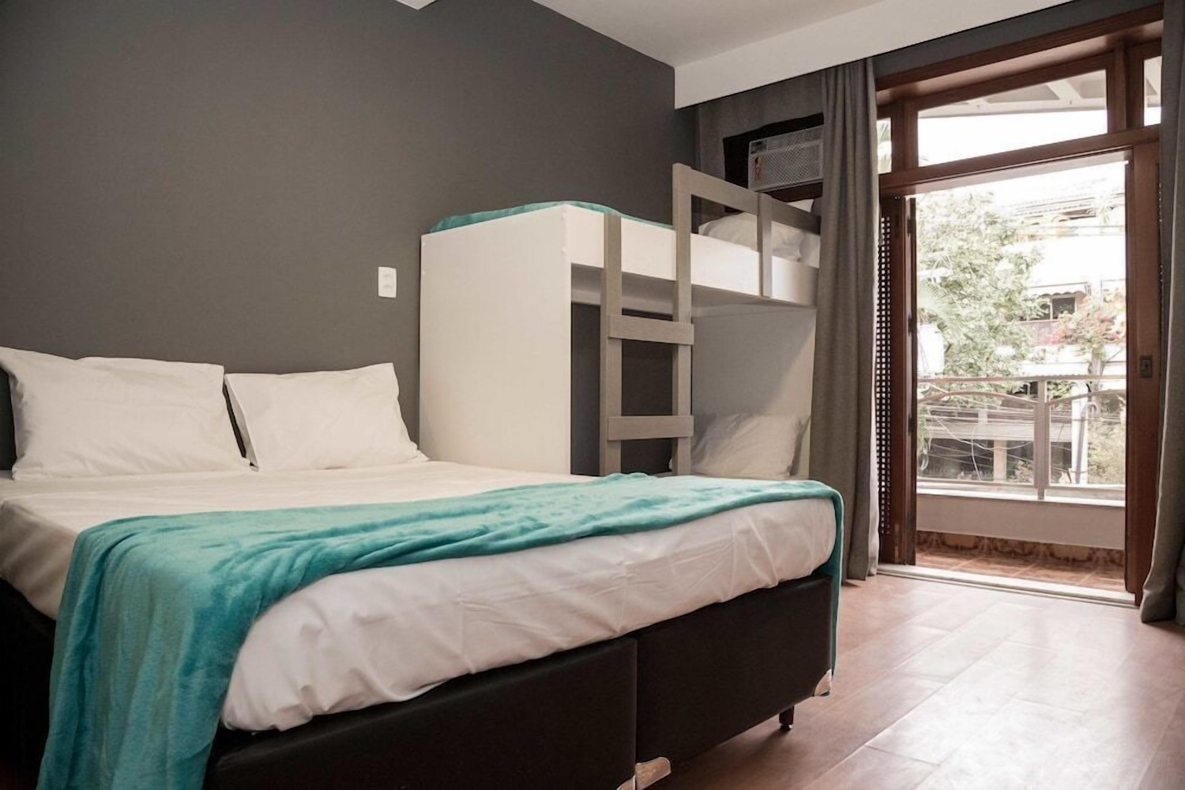 Quarto com beliche, uma janela grande com cortinas, e vista para o exterior.