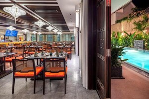 Restaurante com várias mesas e cadeiras, área de piscina com vista e design de interiores moderno.