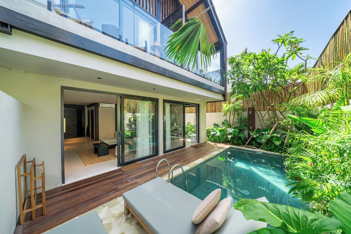 Uma casa moderna com piscina, deck de madeira e vegetação exuberante.