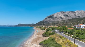 Uma vila costeira com praia, casas e uma montanha ao fundo.